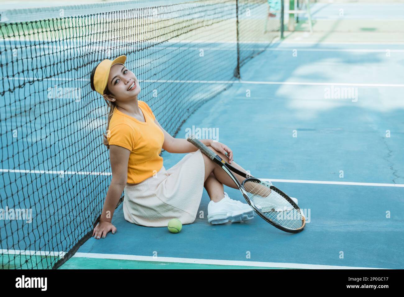 female tennis player sitting in spoiled pose on tennis court Stock ...