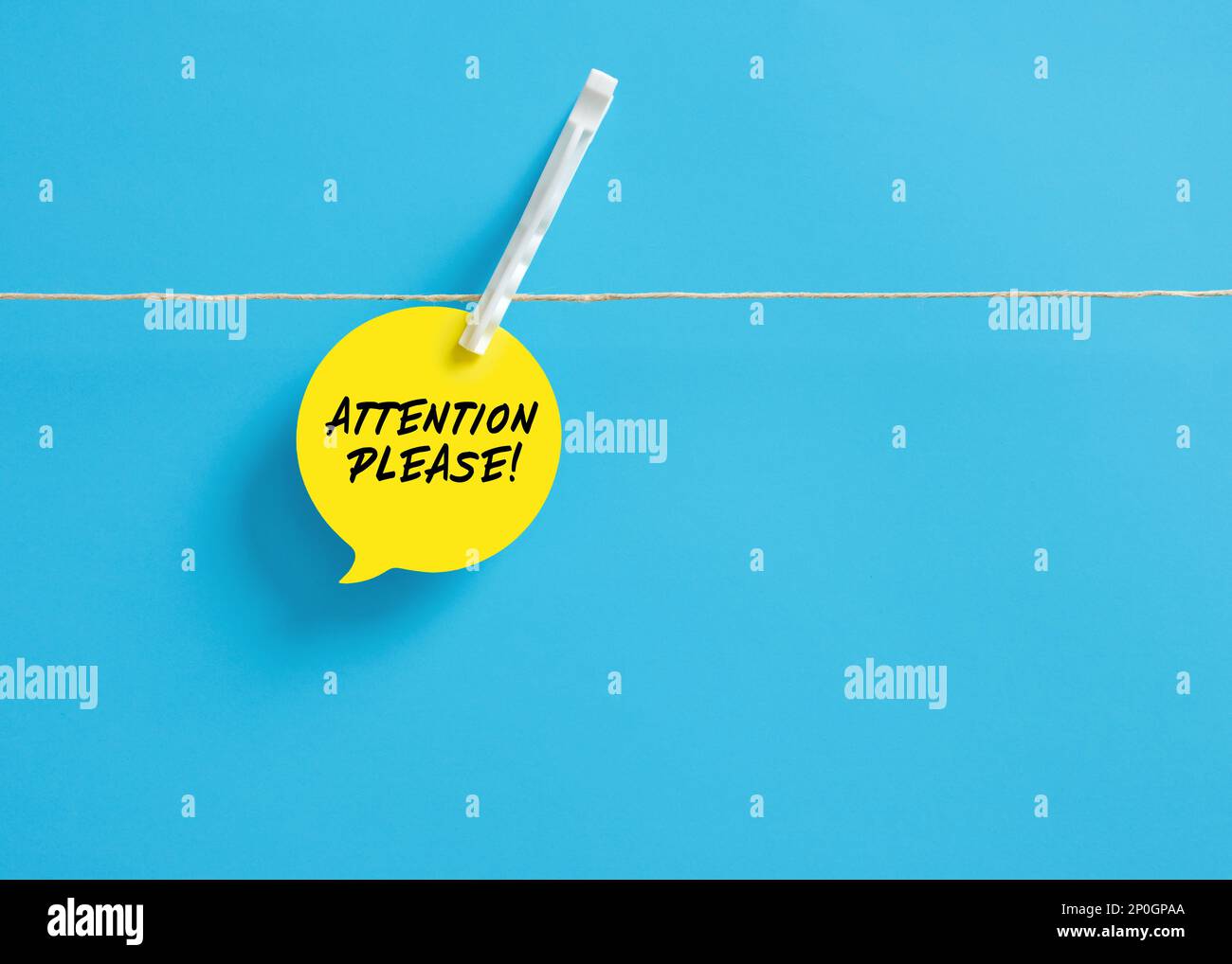 Attention please message on a speech bubble hanging on clothesline with ...