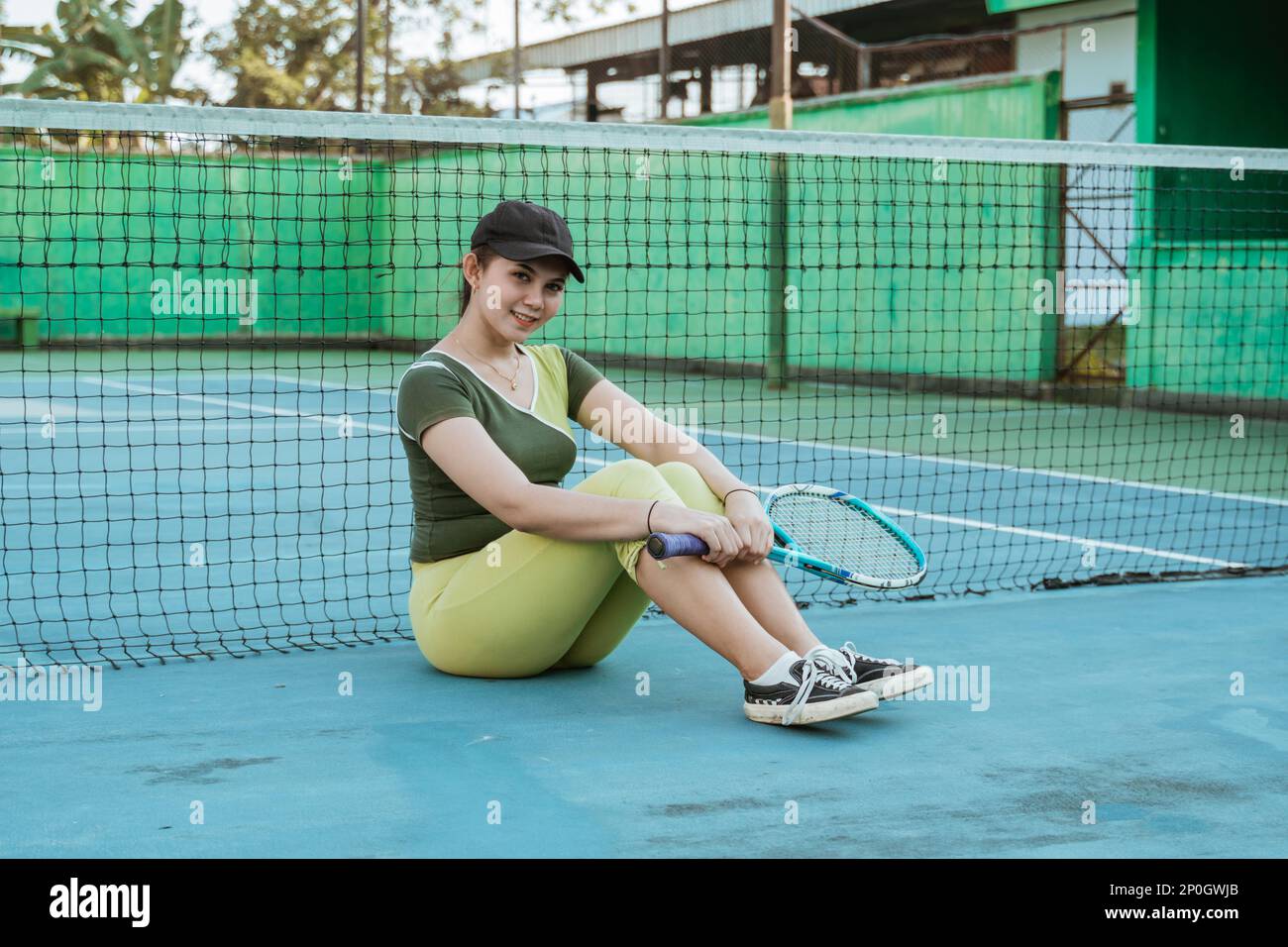 smiling asian female tennis player sitting relaxed holding racket Stock ...