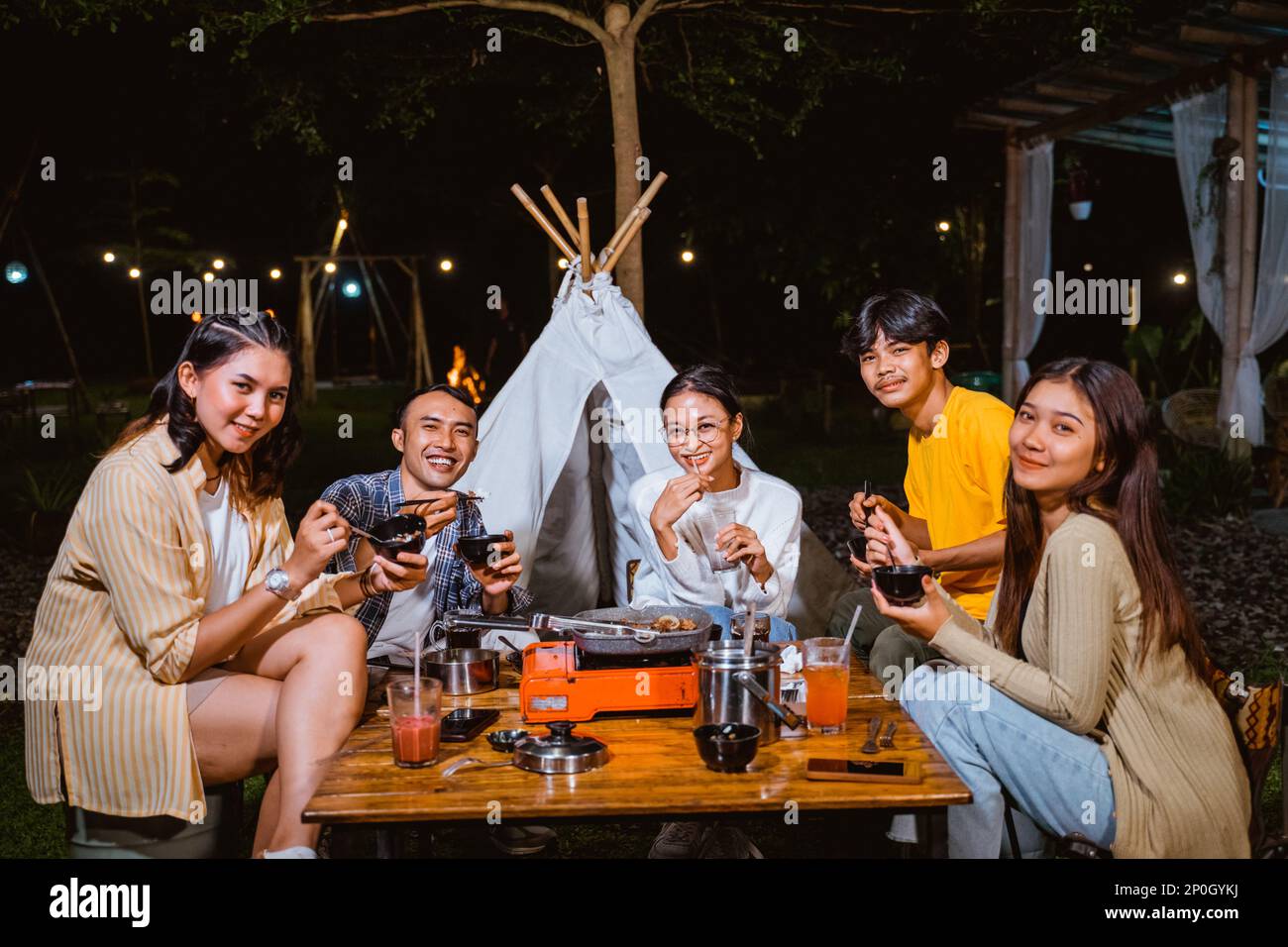 a group of people smiling and eating the grilled beef together Stock ...