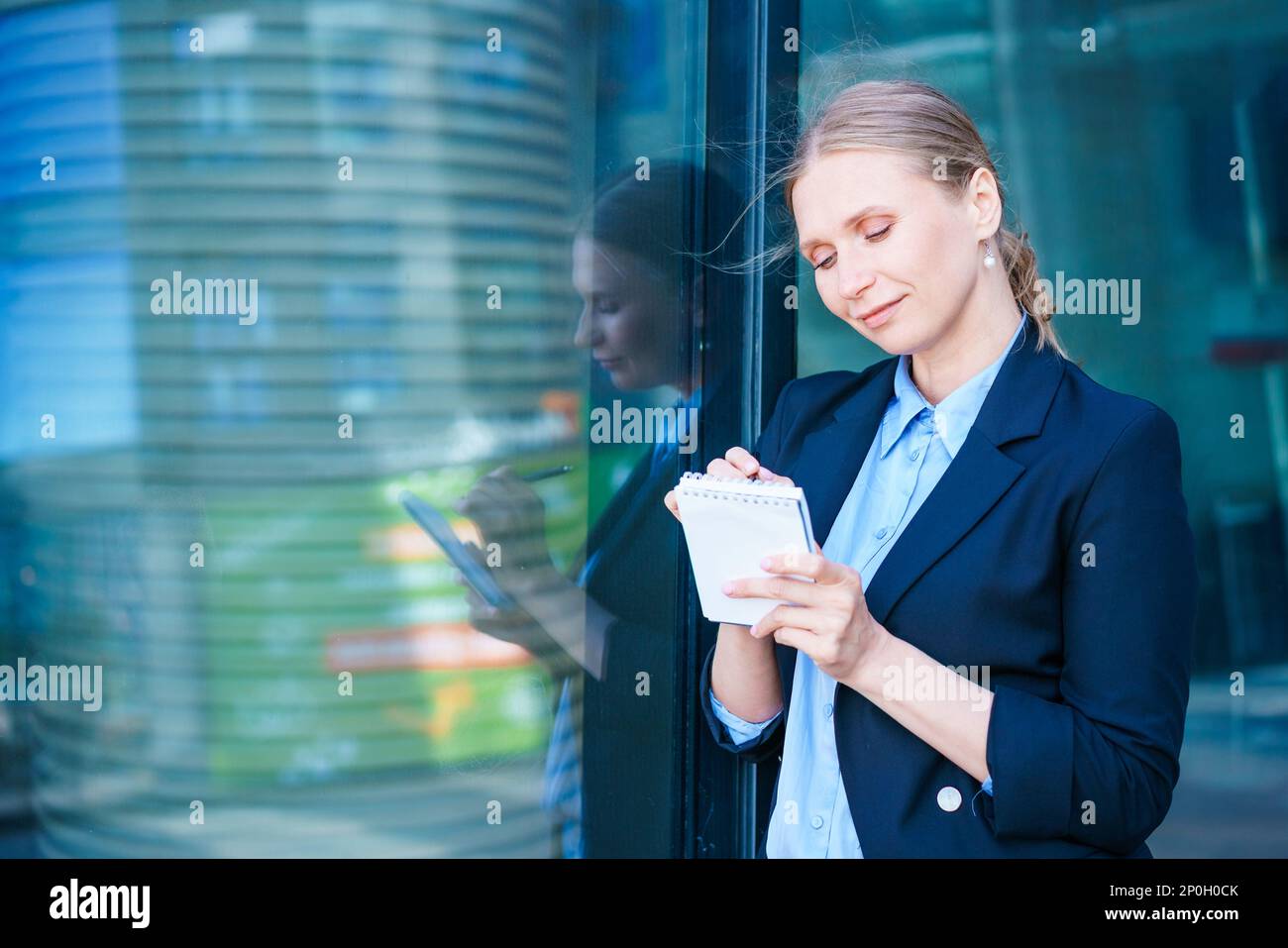 Successful female banker using smart phone outdoors while standing near ...