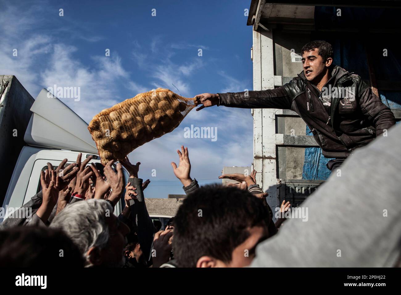 An Iraqi man distributes potatoes to civilians in the Samah district of ...