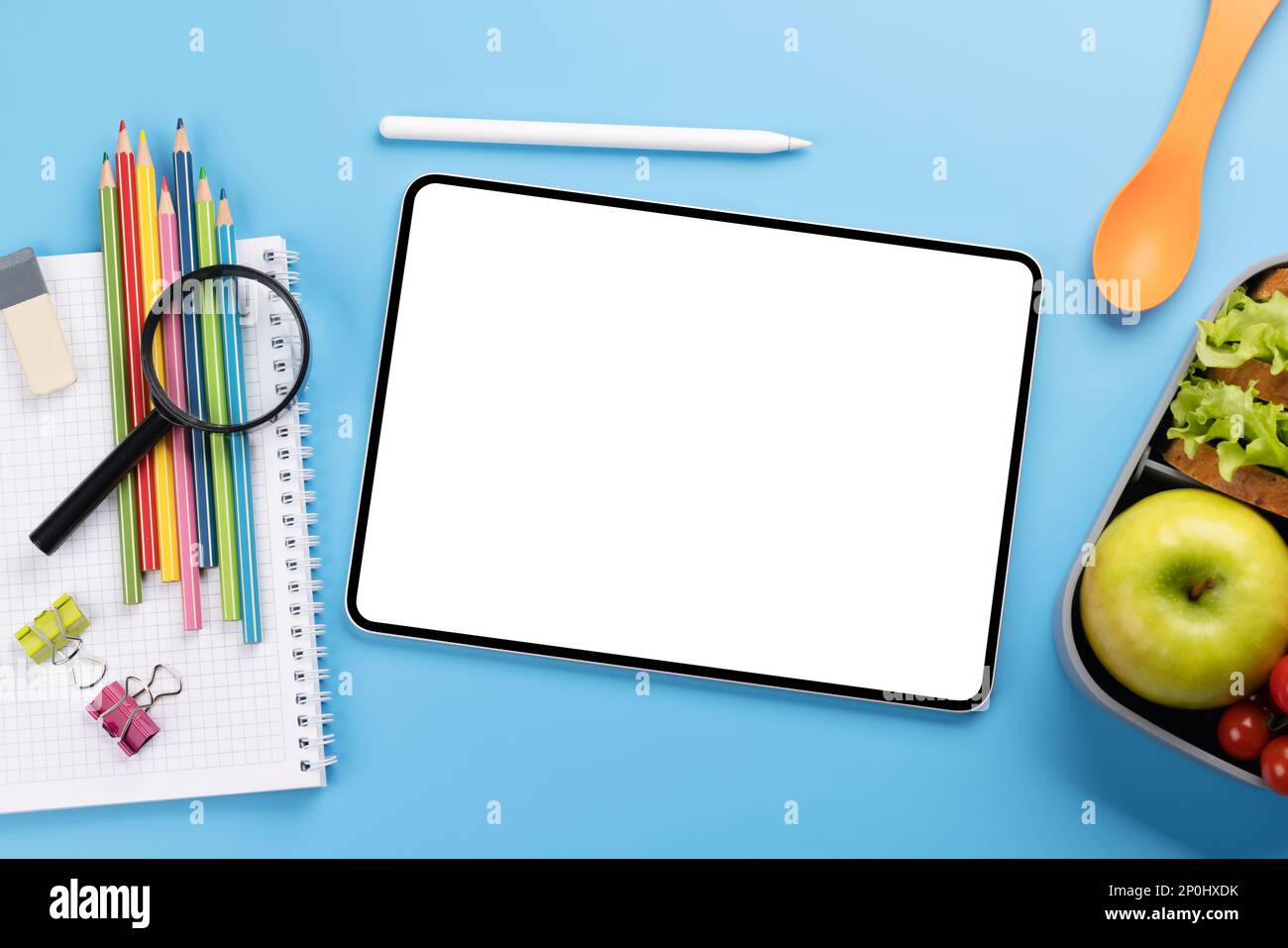 Tablet with blank screen, school supplies, stationery, and lunch box on ...
