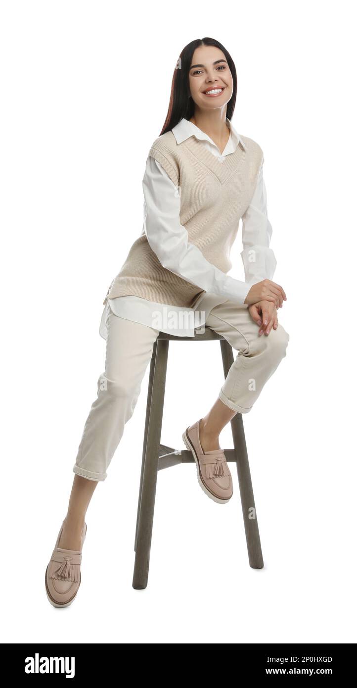 Beautiful young woman sitting on stool against white background Stock ...