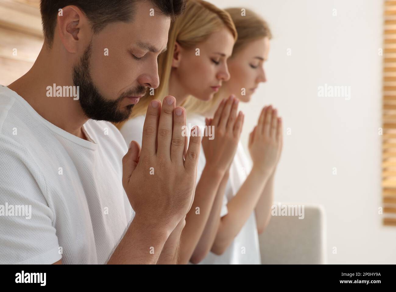 Group of religious people praying together indoors. Space for text ...