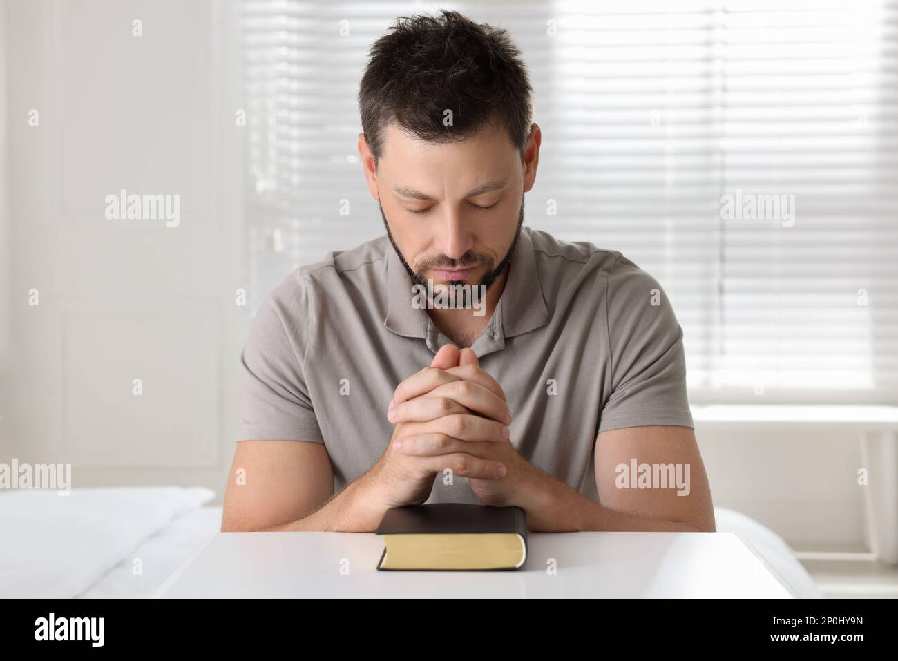 Religious man with Bible praying at home Stock Photo - Alamy