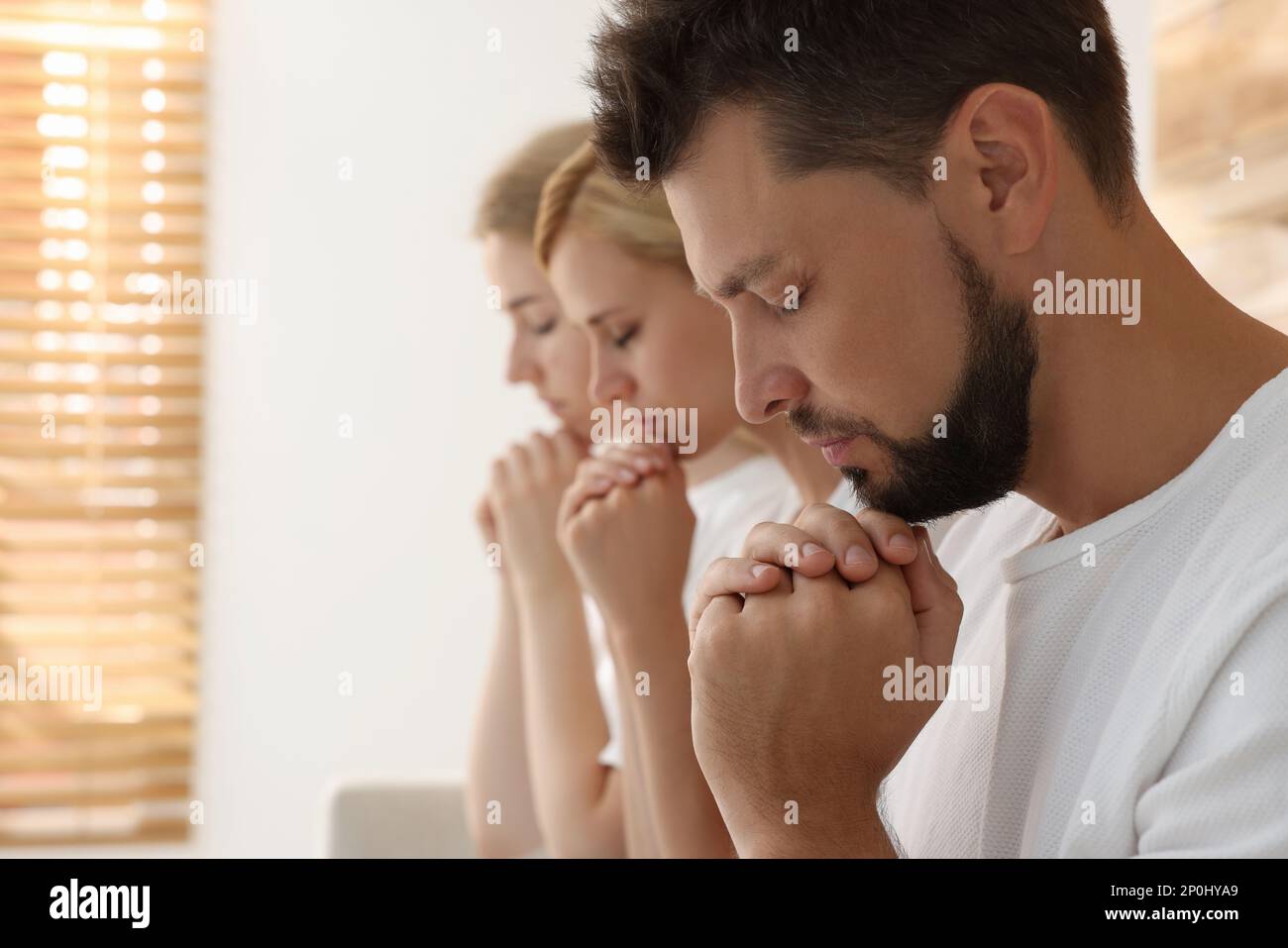 Group of religious people praying together indoors. Space for text ...