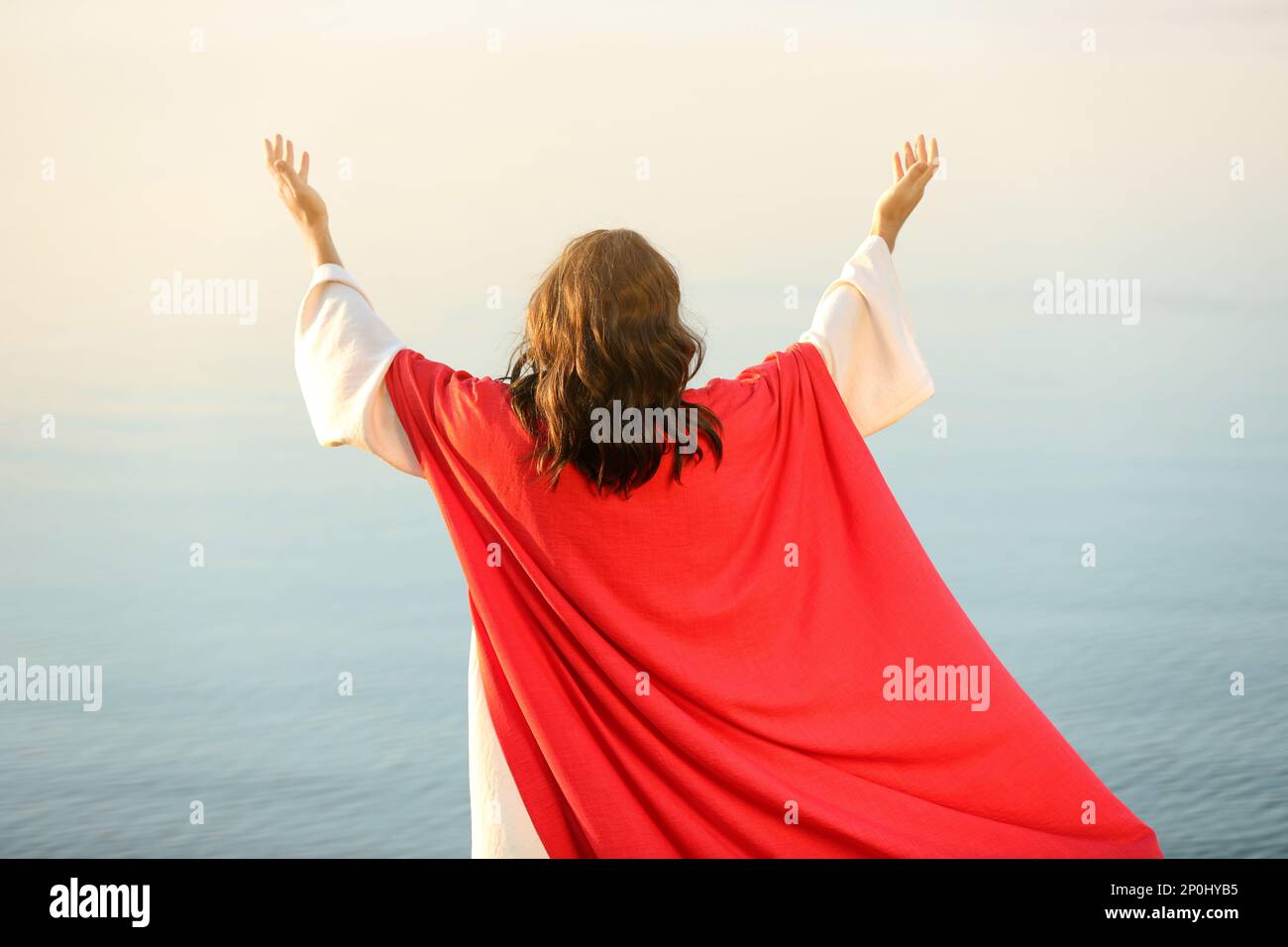 Jesus Christ raising hands near water outdoors, back view Stock Photo ...