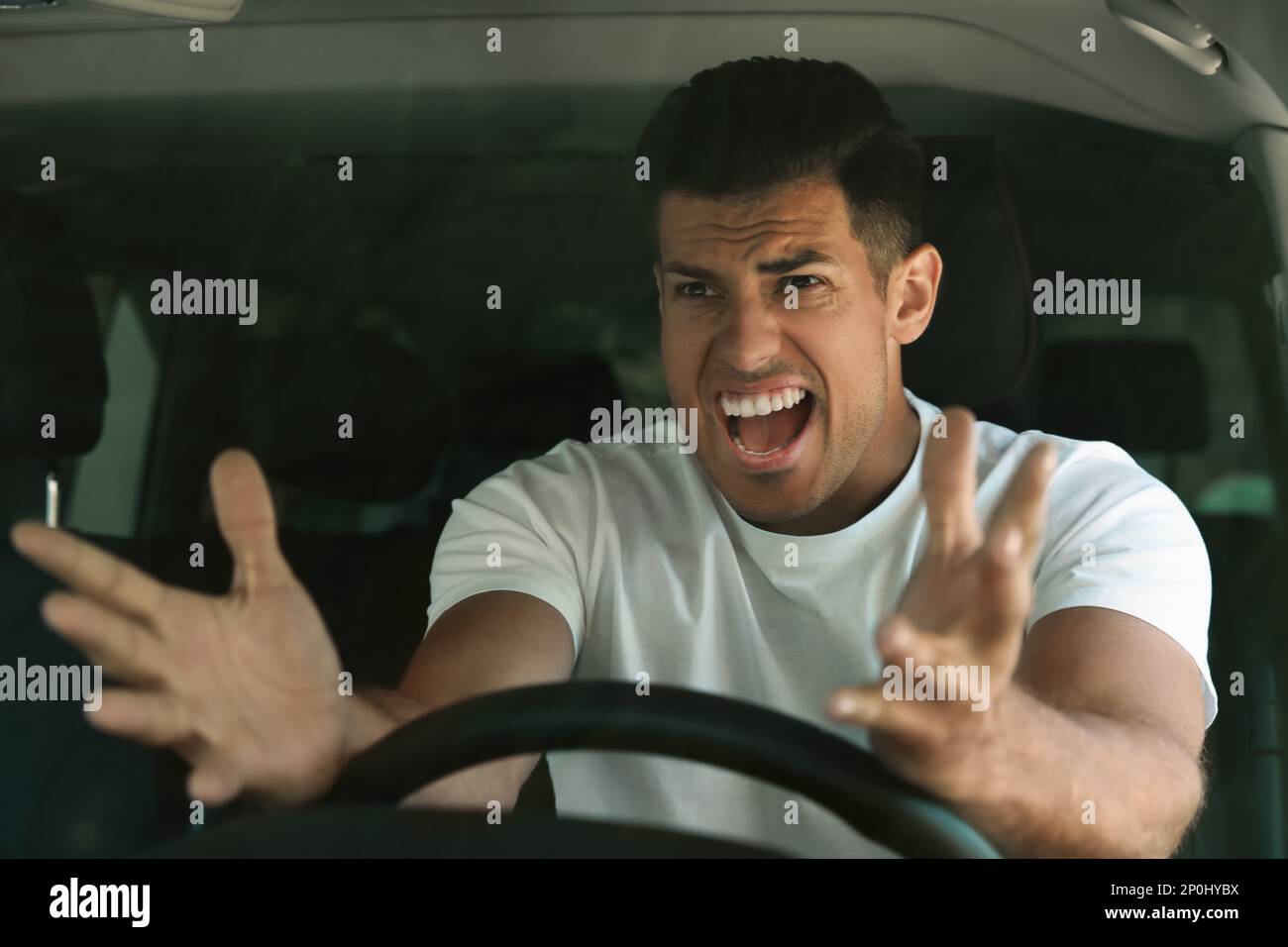 Stressed angry man in driver's seat of modern car, view through ...