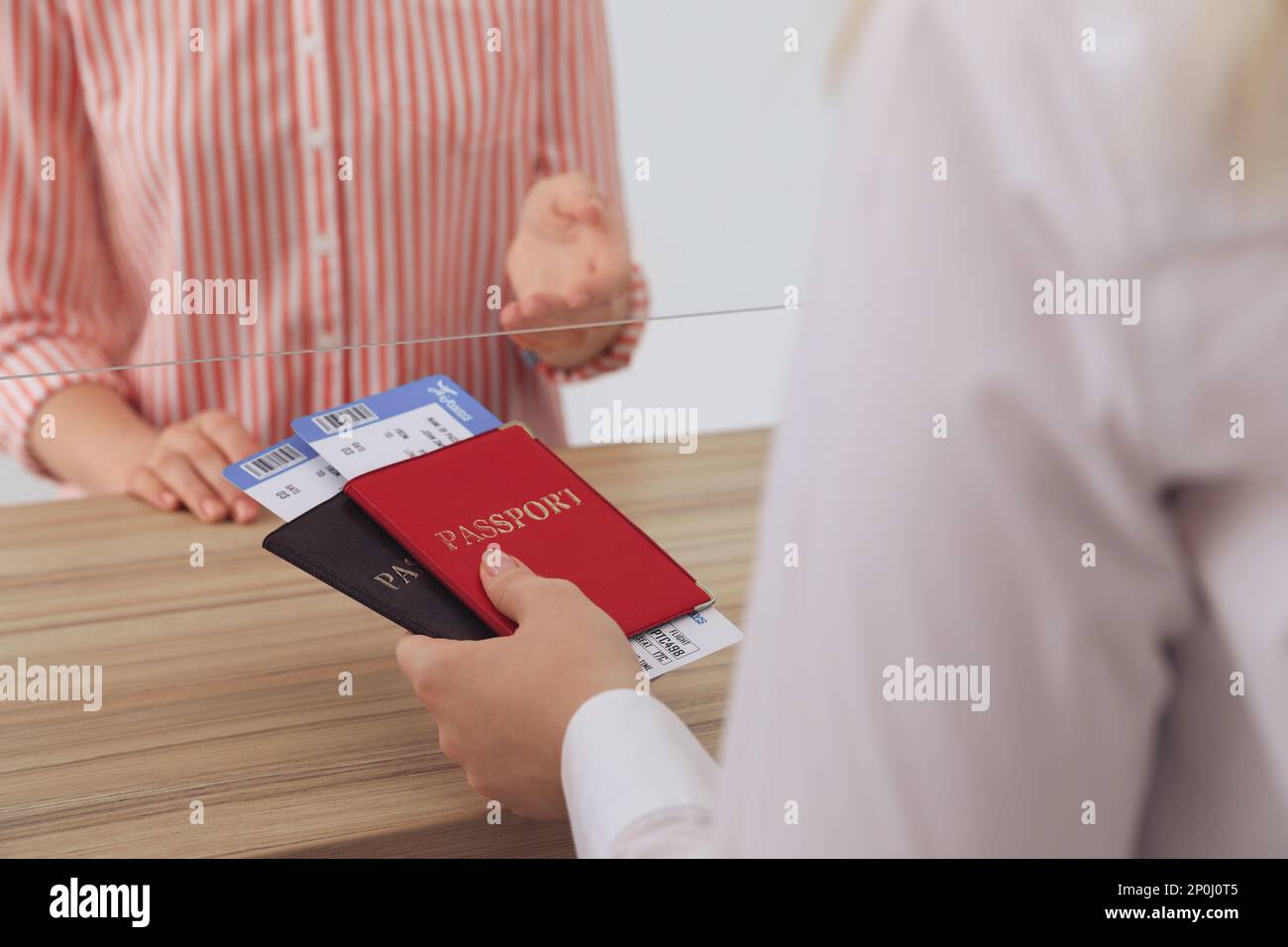 Agent giving passports with tickets to client at check-in desk in ...