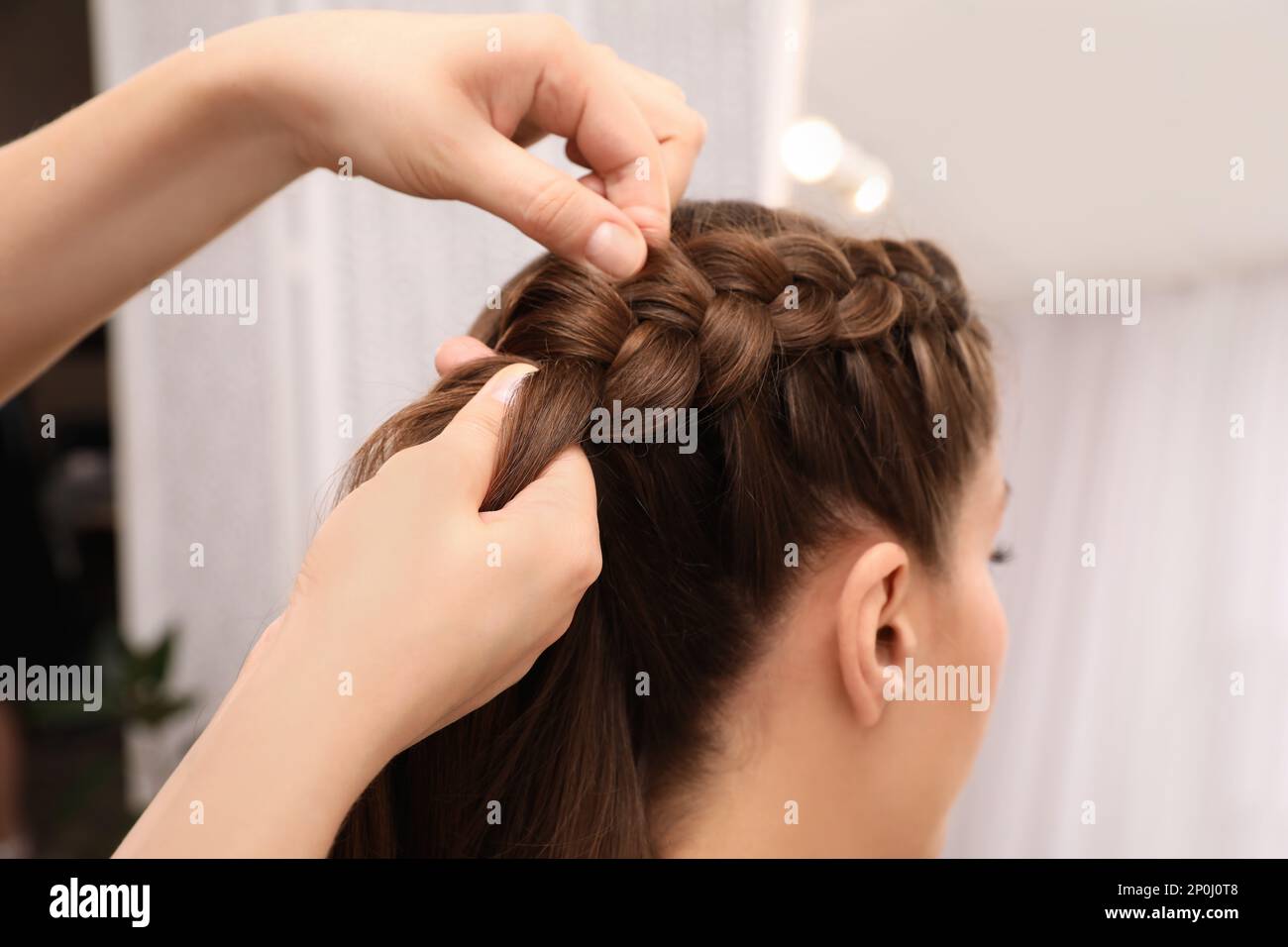 Professional stylist braiding client's hair in salon, closeup Stock ...