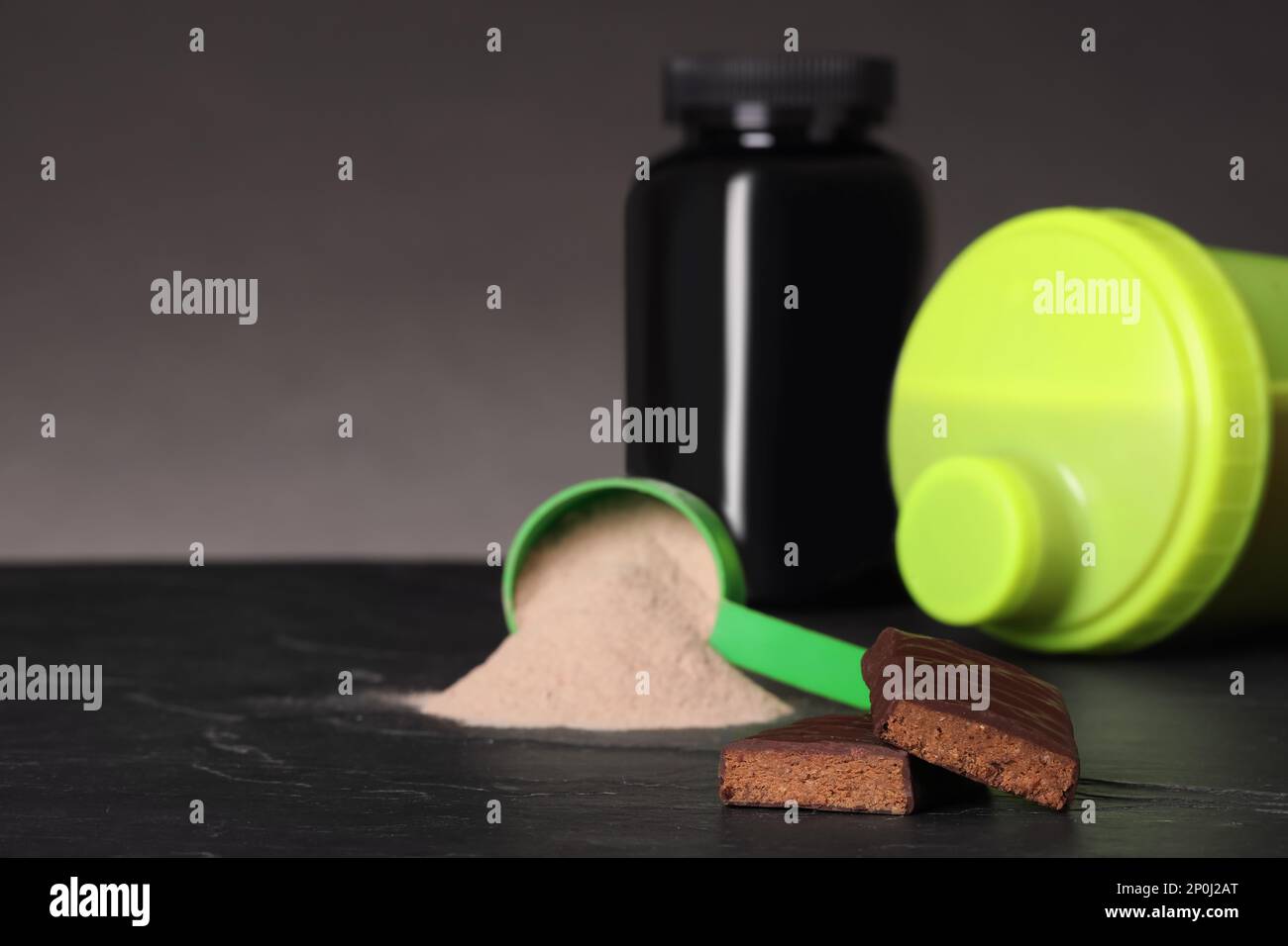 Different energy bars, protein cocktail and powder on black table ...