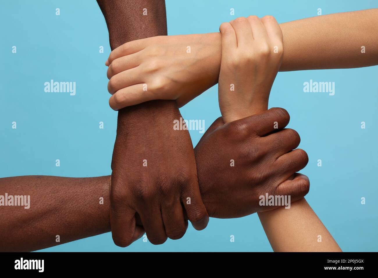 Woman and African American man joining hands together on light blue ...