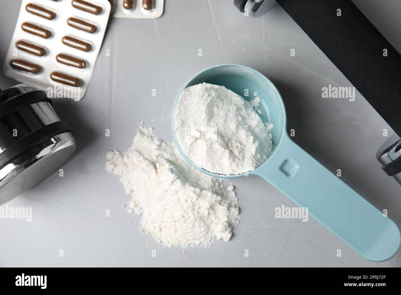 Measuring scoop of amino acids powder, pills and dumbbells on light ...