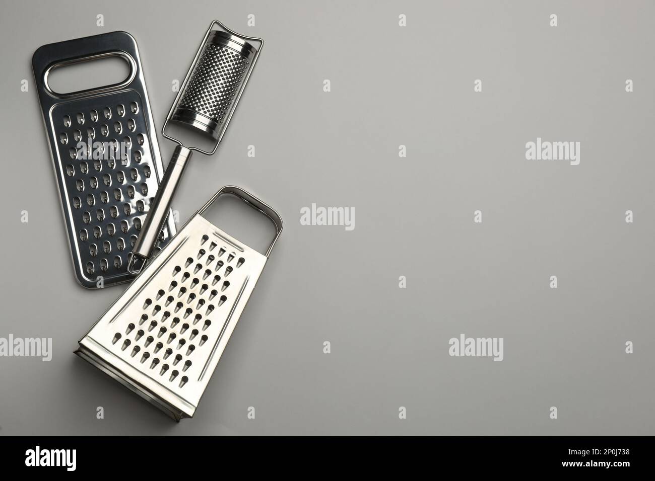 Different modern graters on grey background, flat lay. Space for text ...
