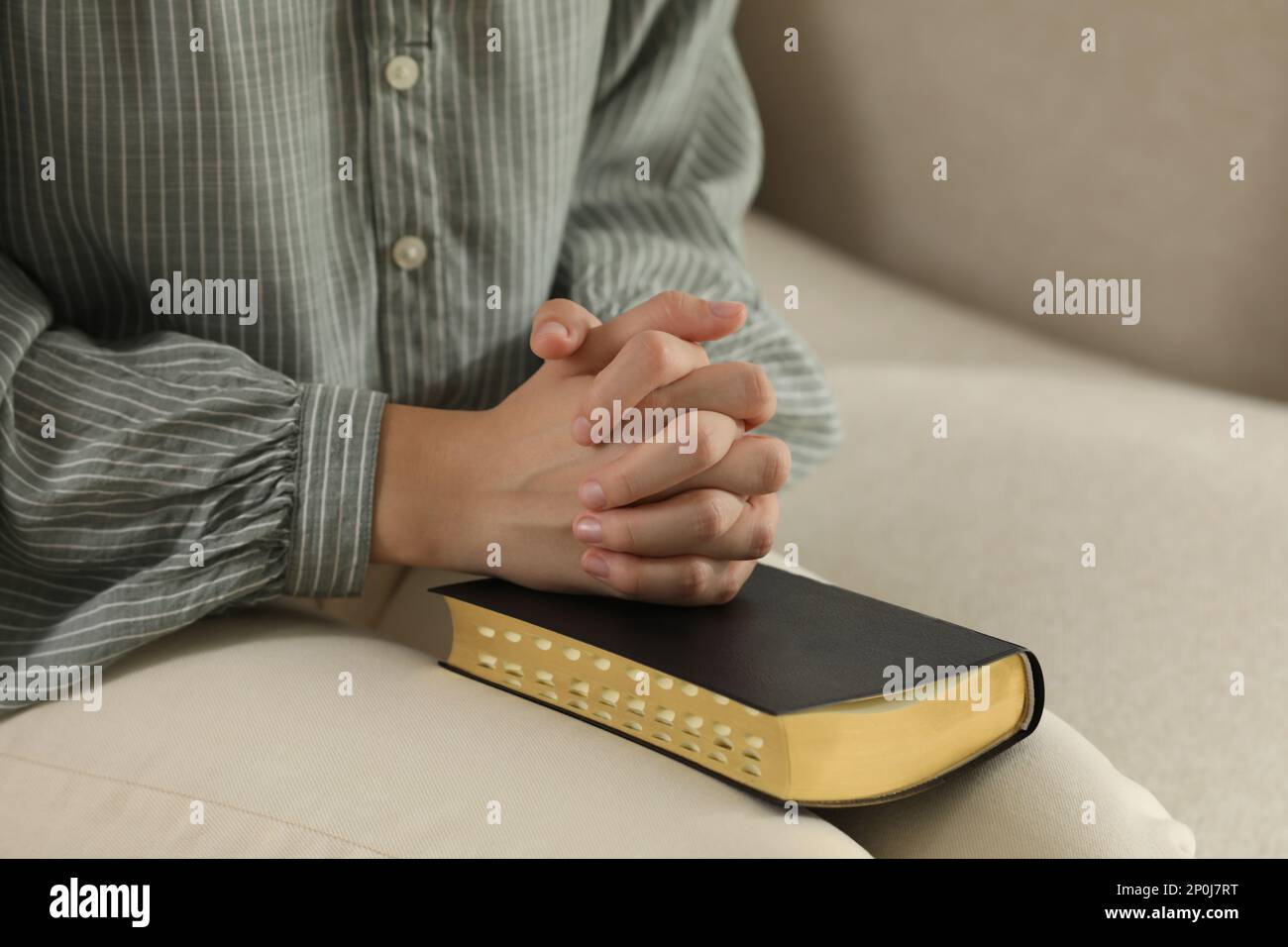 Religious woman praying over Bible on sofa, closeup Stock Photo - Alamy