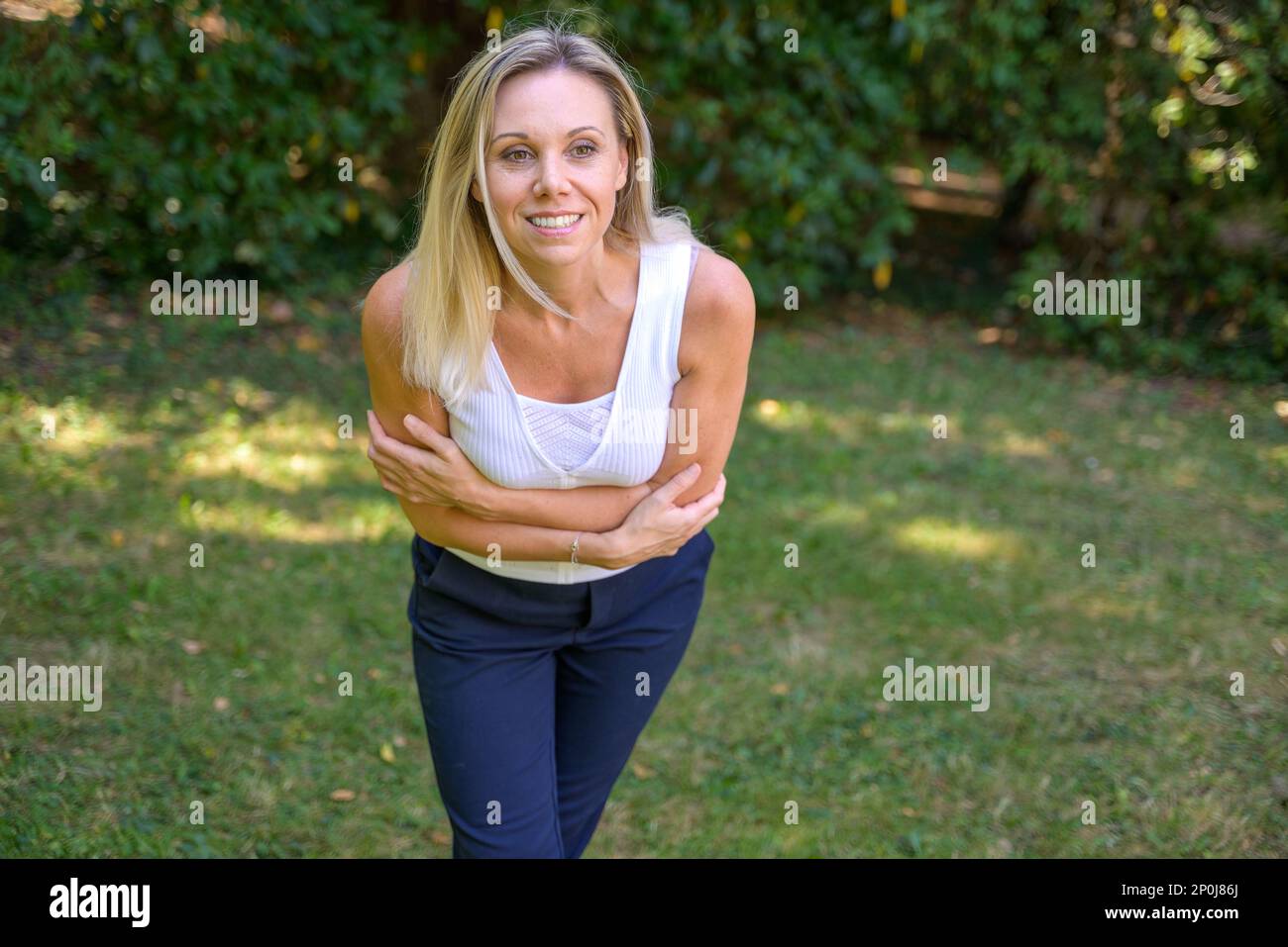Blond woman leaning to the camera as she clasps her chest looking aside ...