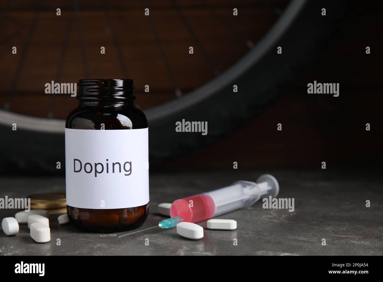 Pills, syringe and bike wheel on grey table. Using doping in cycling ...