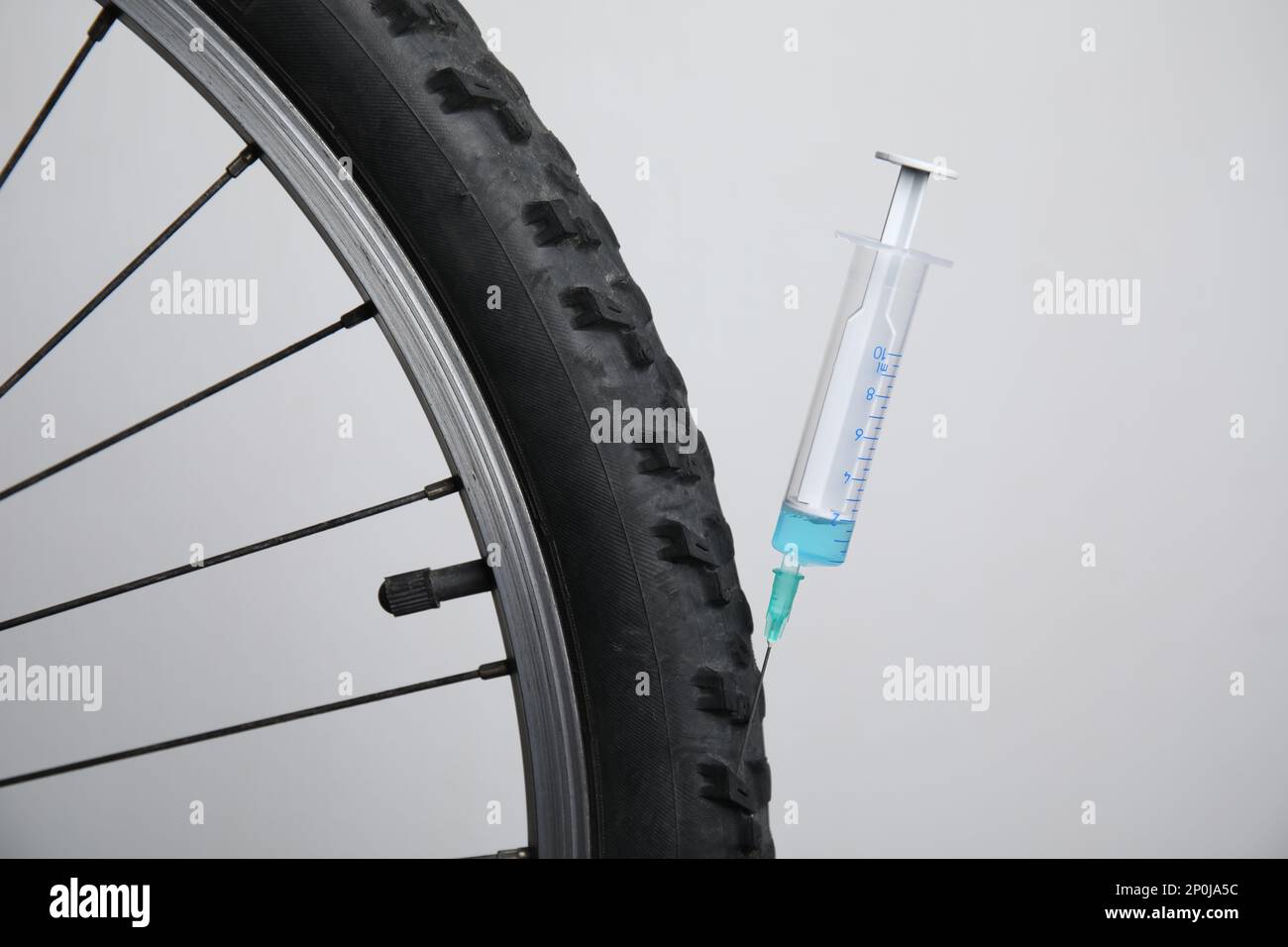 Bike wheel with syringe on light background, closeup. Using doping in ...