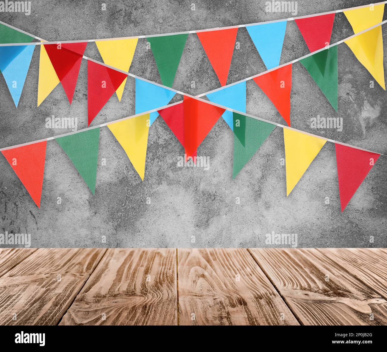 Empty wooden table and decorative bunting flags hanging on grey wall ...