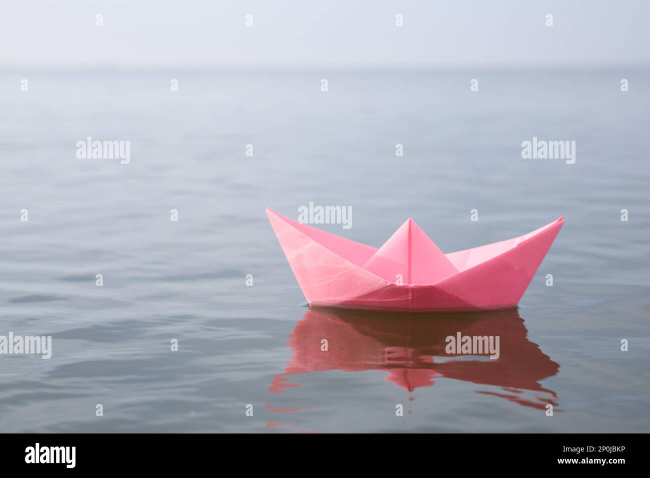 Pink paper boat on water surface, space for text Stock Photo - Alamy