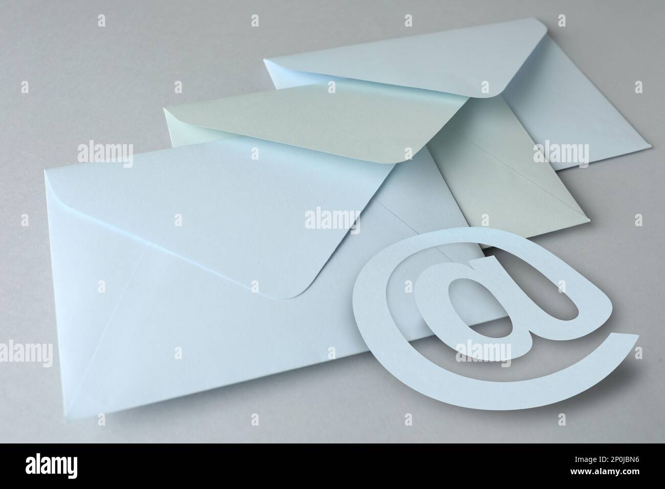 White paper envelopes and at sign on light grey background, closeup ...