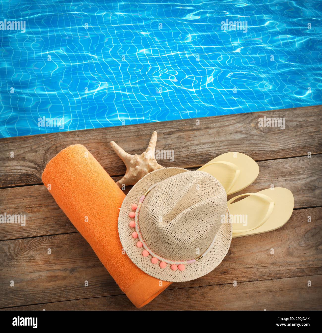 Beach towel, flip flops, straw hat and starfish on wooden surface near ...