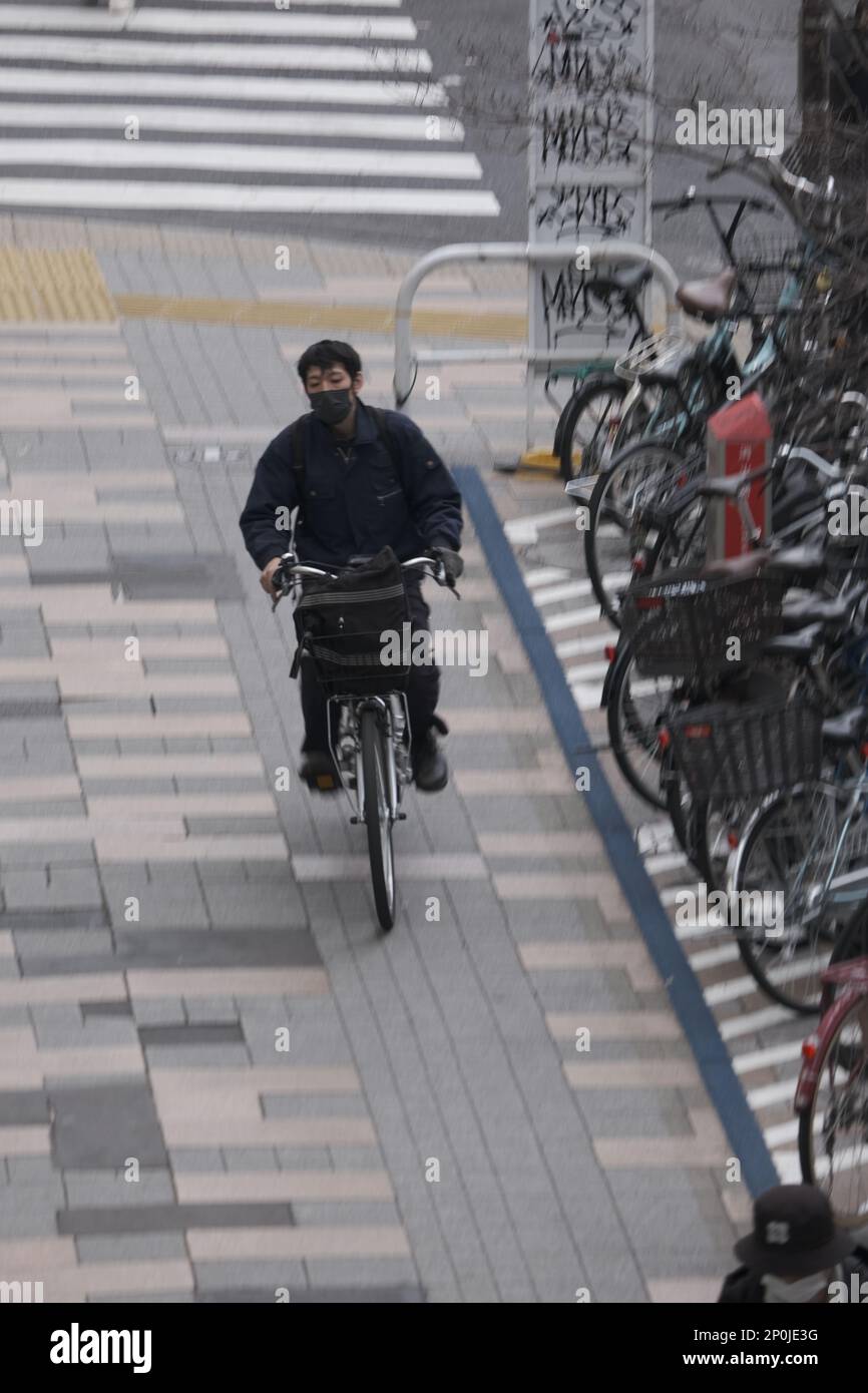 Man riding bike through streets on Japan Stock Photo - Alamy