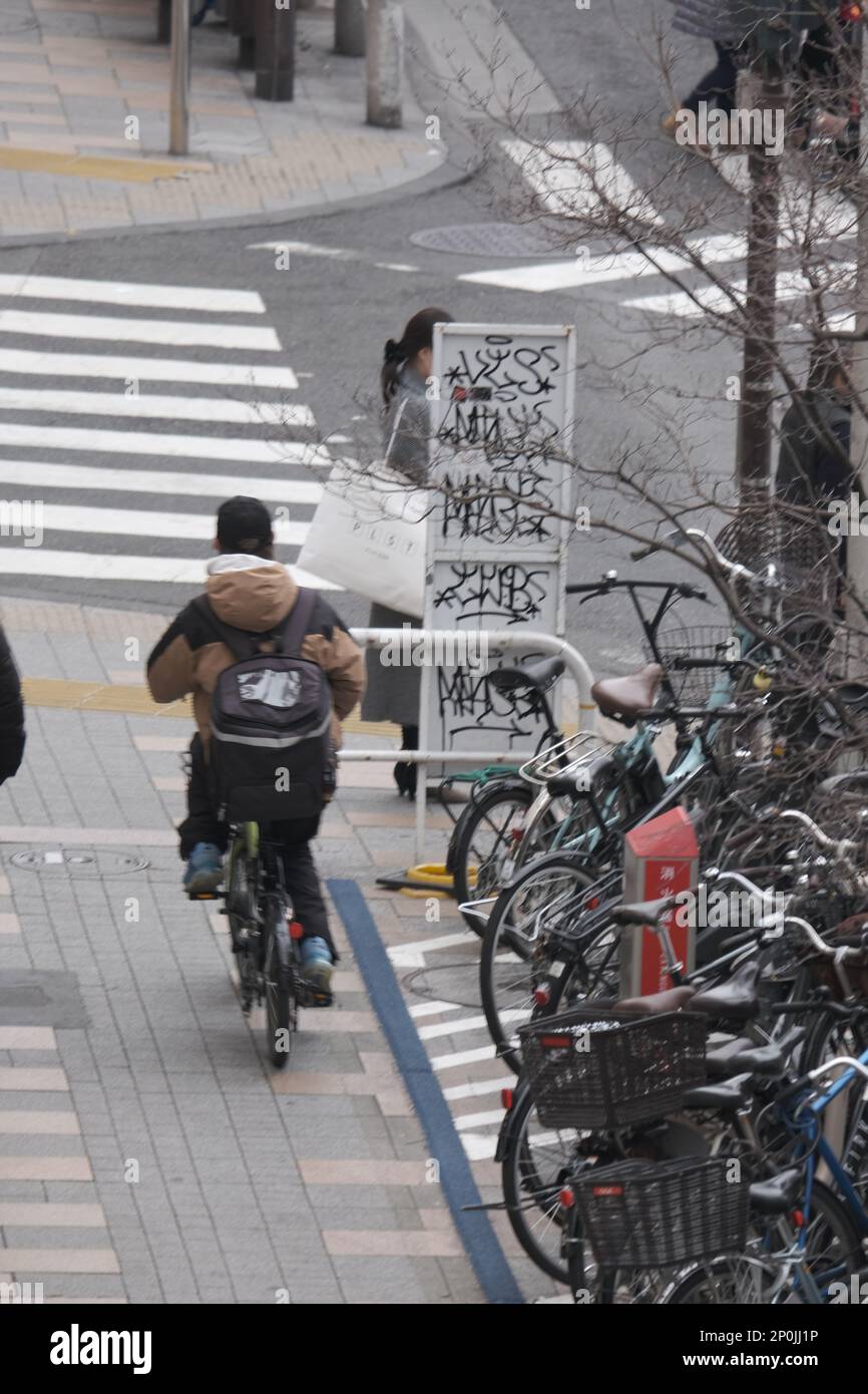 Man riding bike through streets on Japan Stock Photo - Alamy