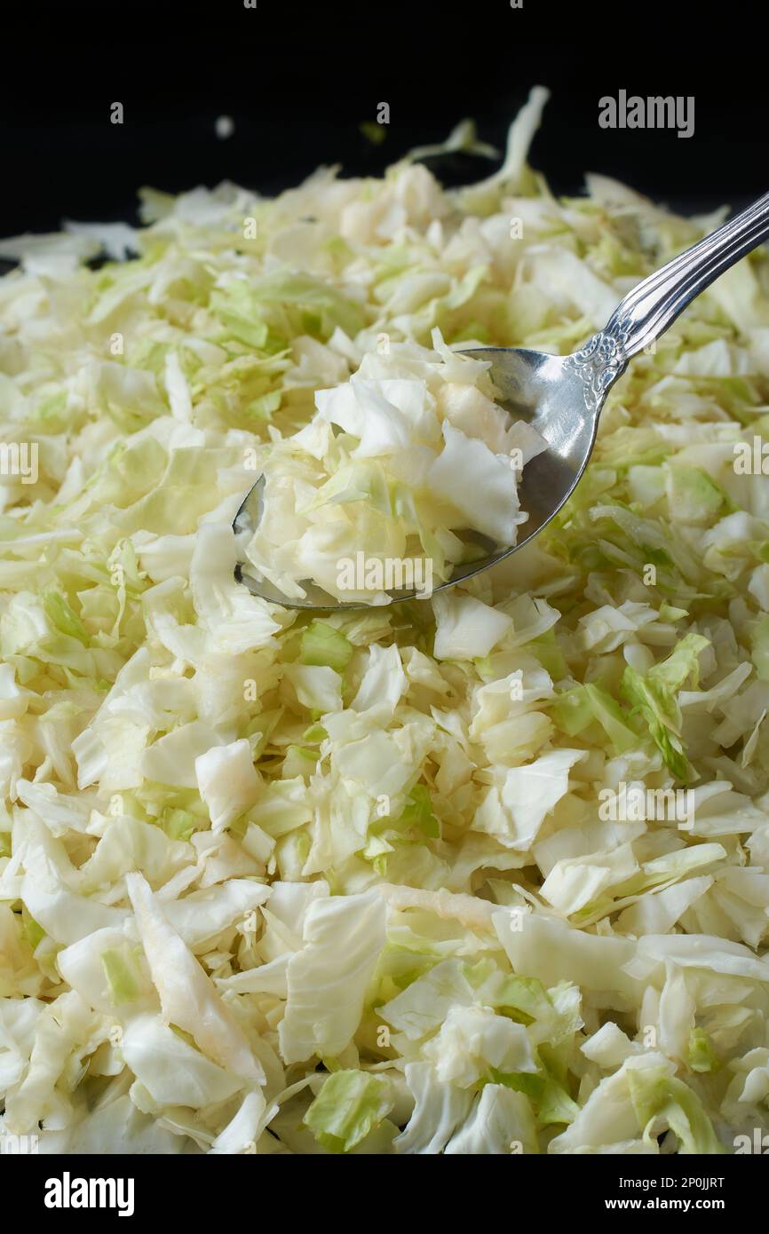 pile of chopped green cabbage leaves with silver spoon, white and pale ...