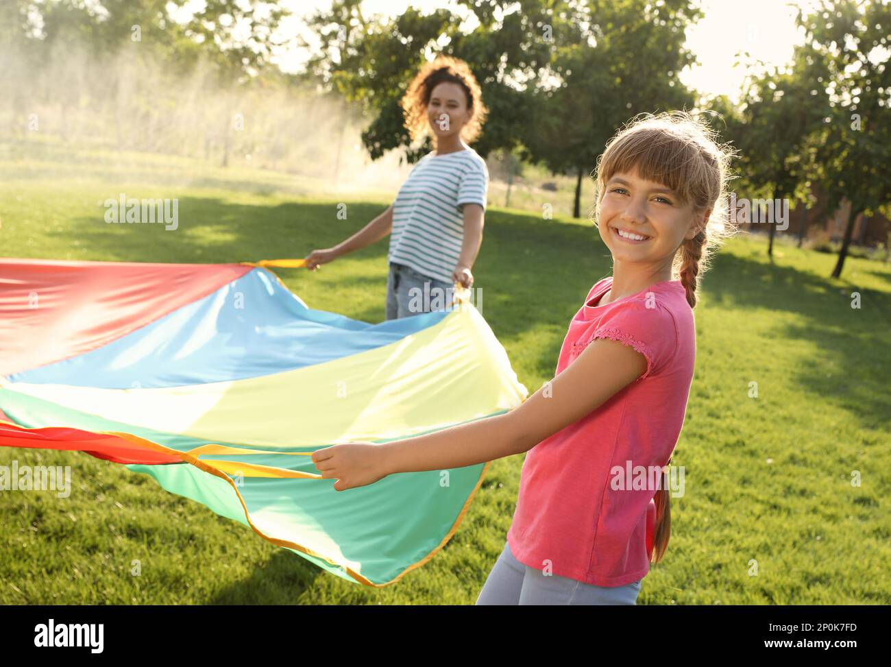 Cute child and African-American teacher playing with rainbow playground ...