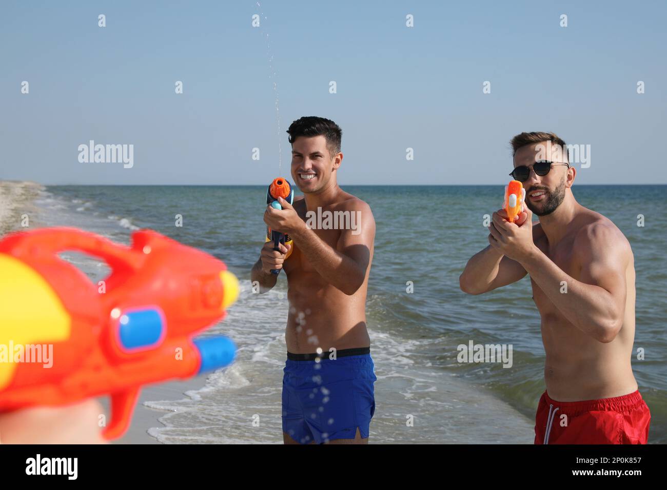 Friends with water guns having fun on beach Stock Photo - Alamy
