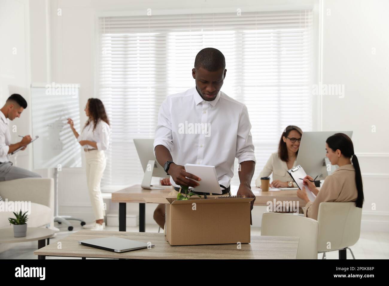 New coworker unpacking box with personal items at workplace in office ...