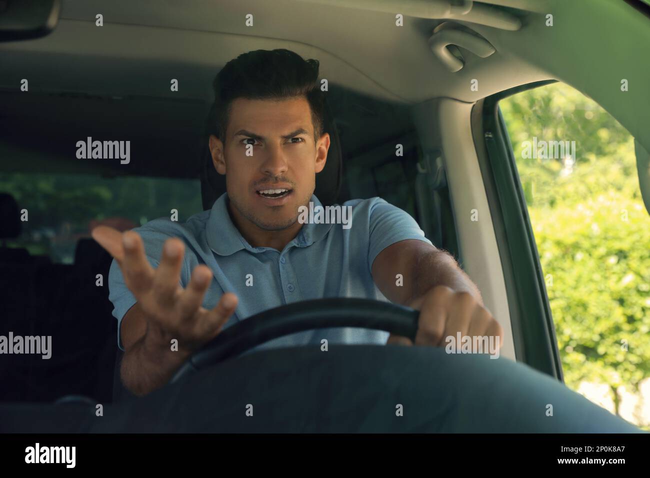 Stressed angry man in driver's seat of modern car, view through ...