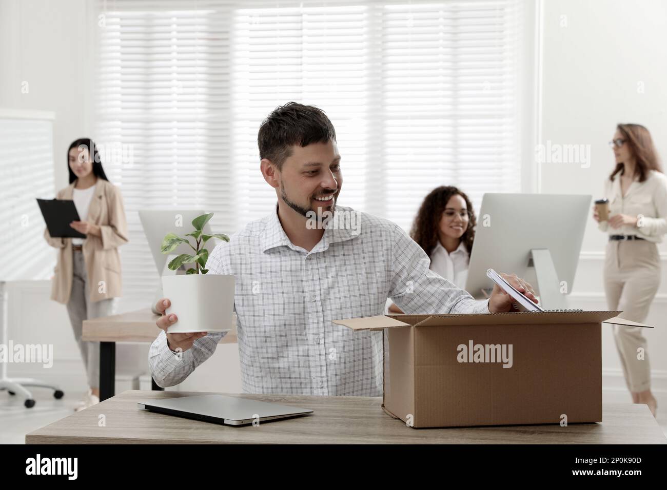 New coworker unpacking box with personal items at workplace in office ...