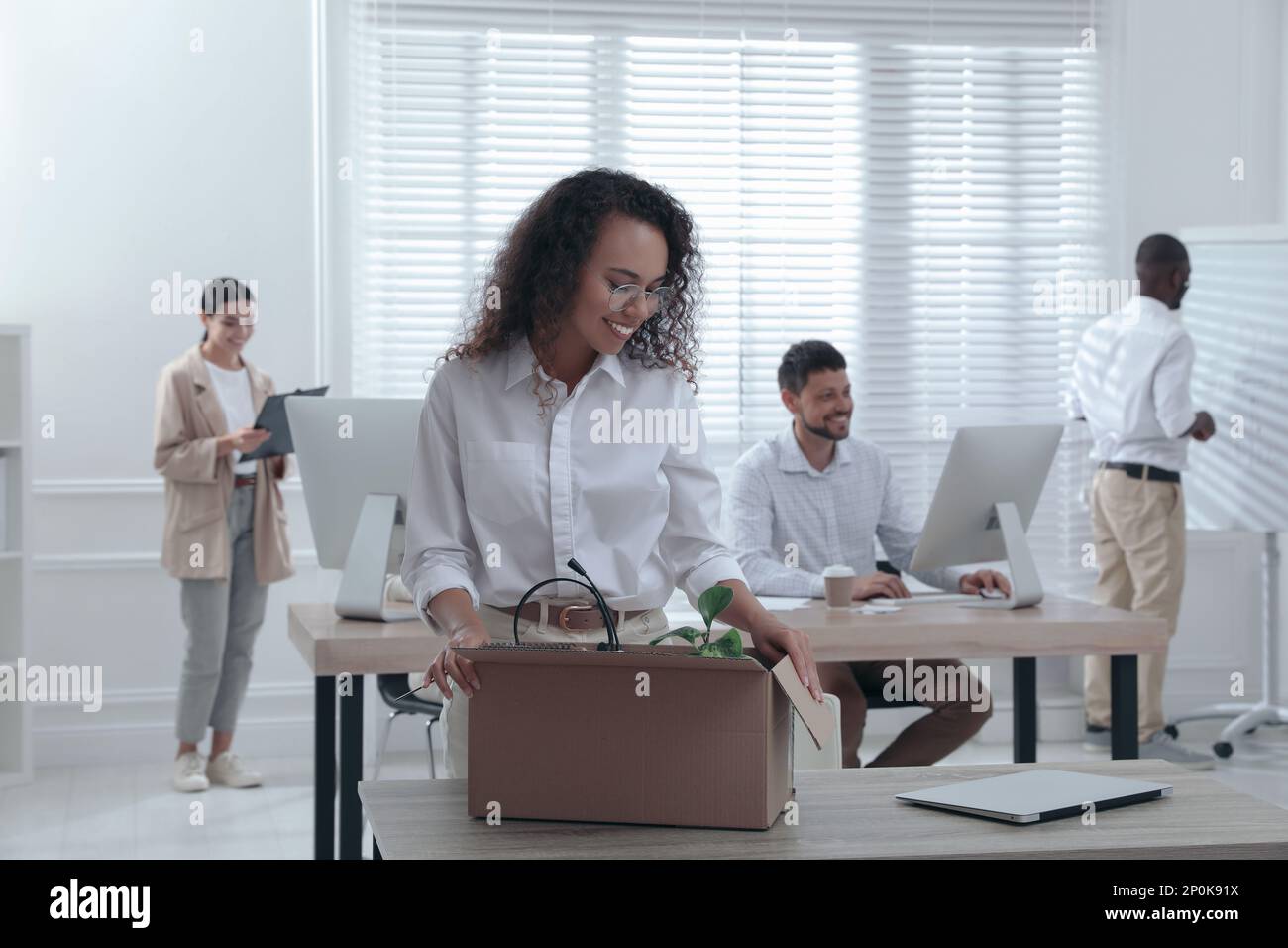 New coworker unpacking box with personal items at workplace in office ...