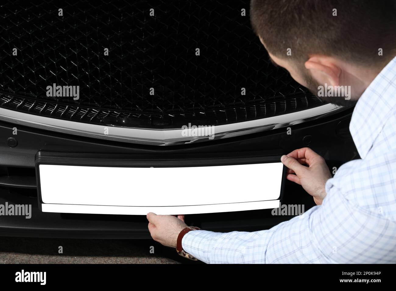 Man installing vehicle registration plate outdoors, closeup. Mockup for ...