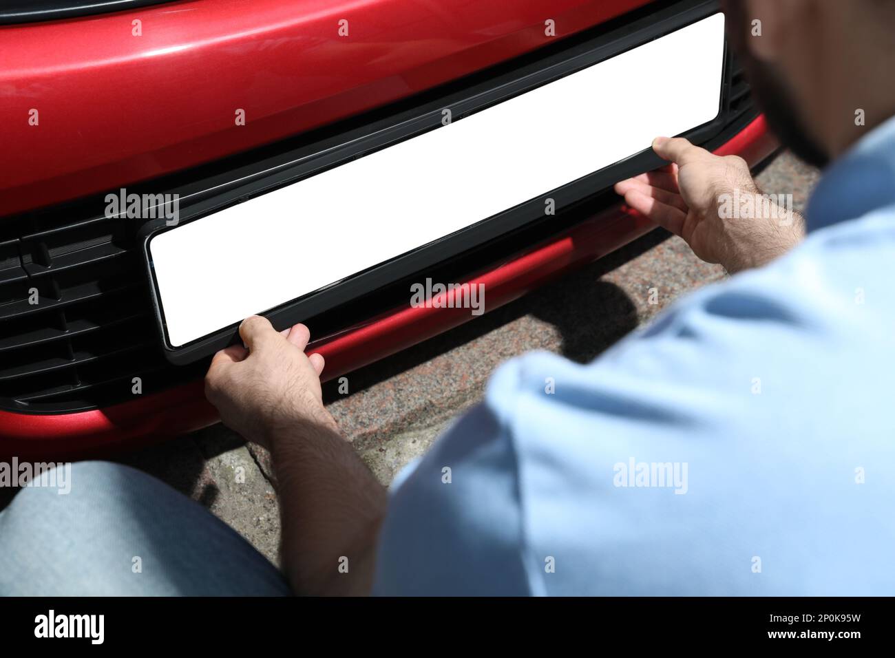 Man installing vehicle registration plate outdoors, closeup. Mockup for ...