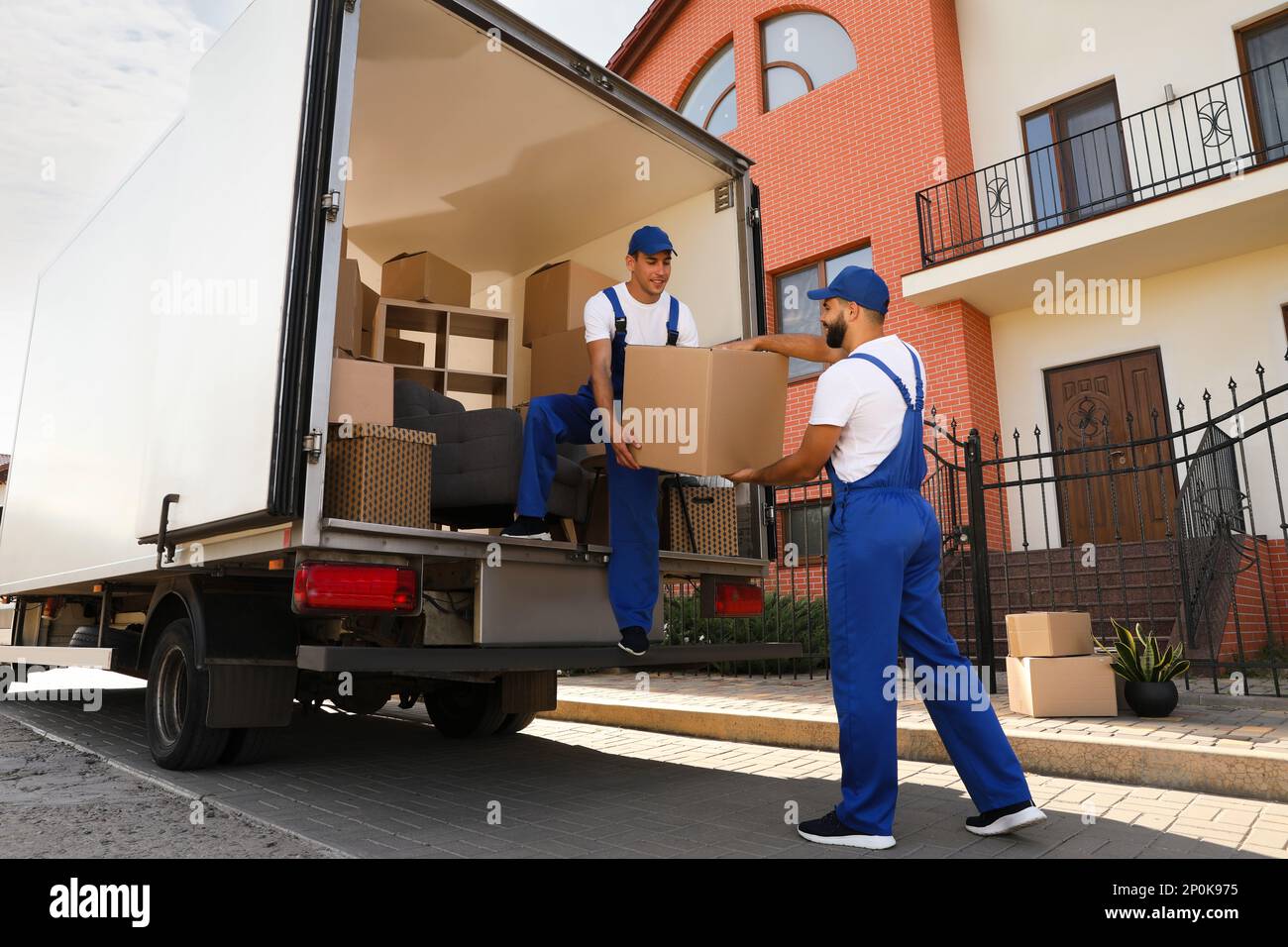 Workers unloading boxes from van outdoors. Moving service Stock Photo - Alamy