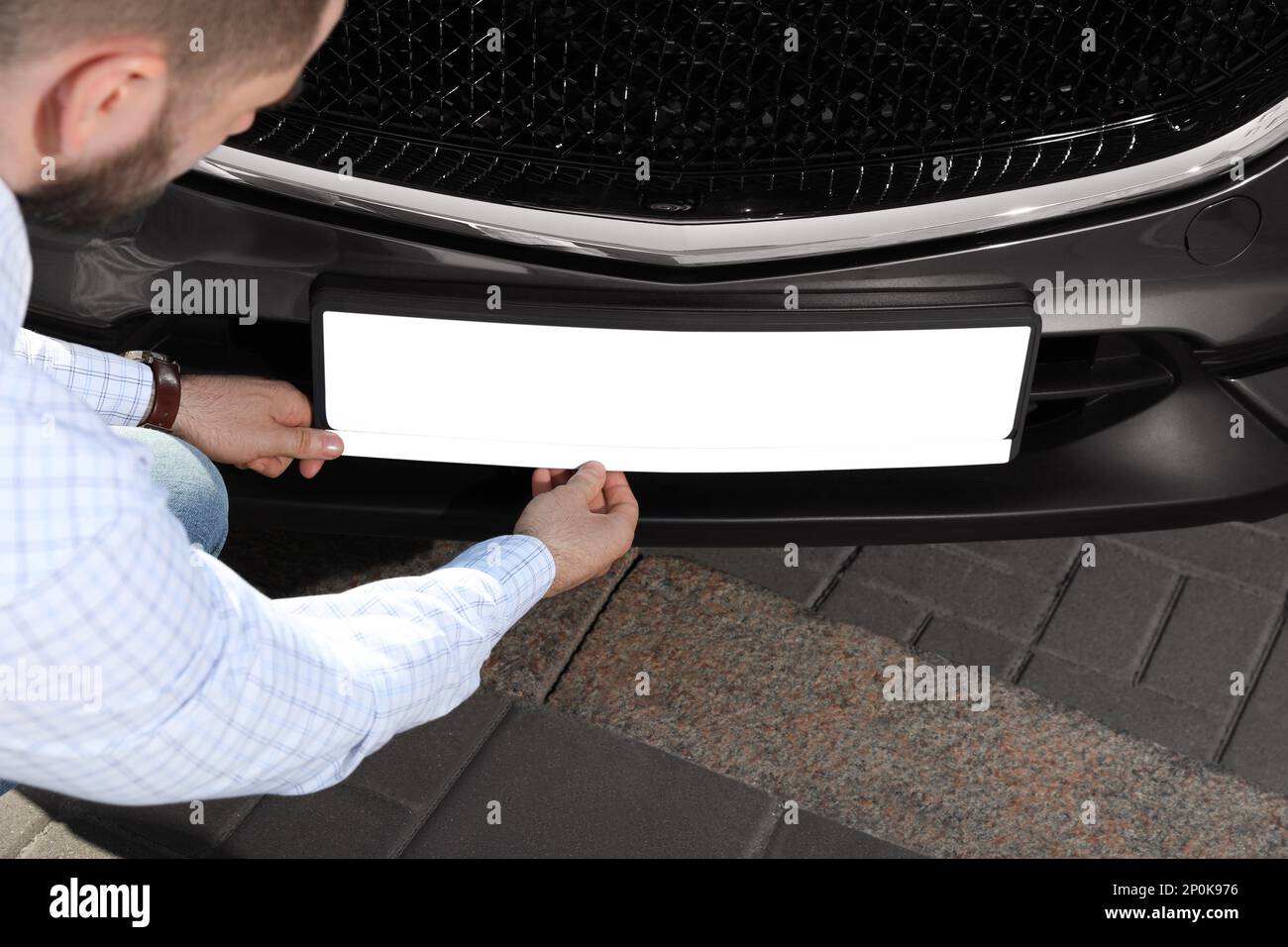 Man installing vehicle registration plate outdoors, closeup. Mockup for ...