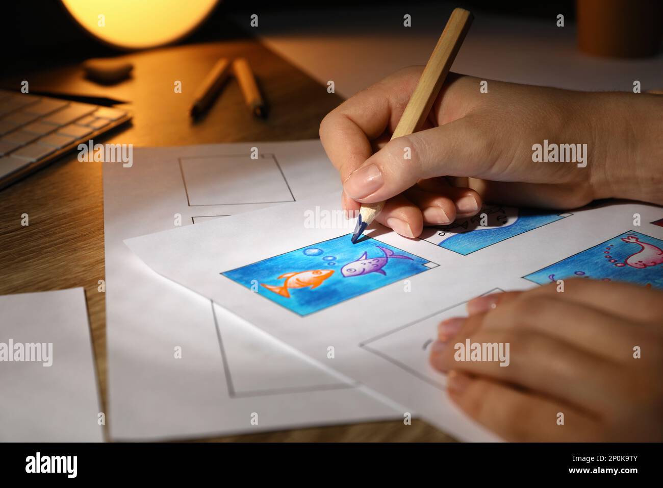 Woman drawing cartoon sketch in storyboard at workplace, closeup. Pre ...