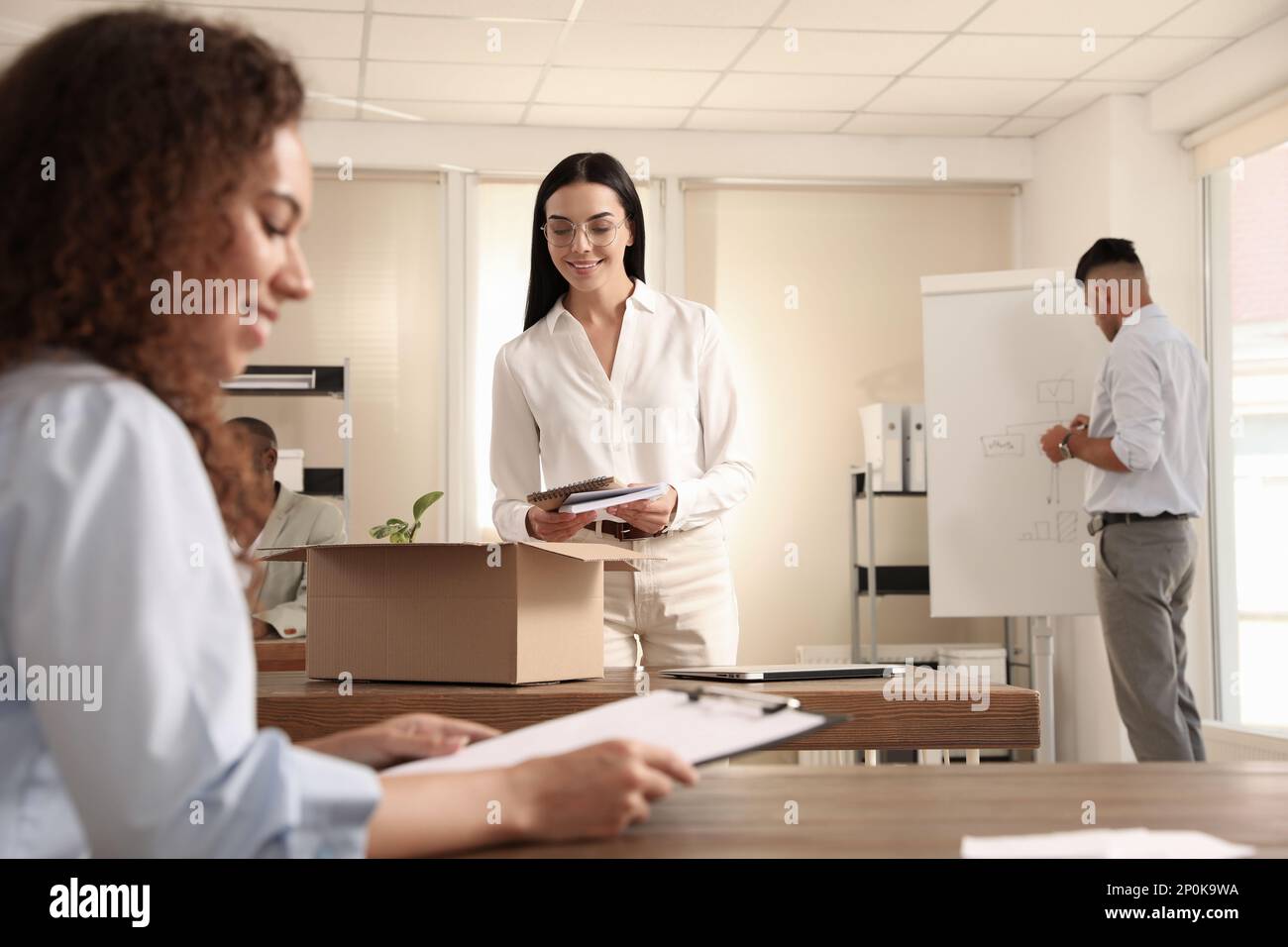 New coworker unpacking box with personal items at workplace in office ...
