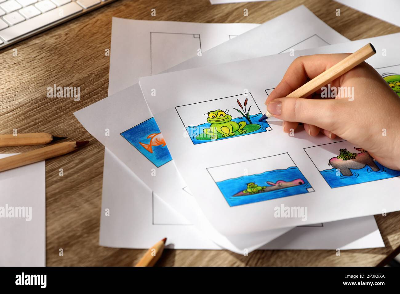 Woman drawing cartoon sketch in storyboard at workplace, closeup. Pre ...