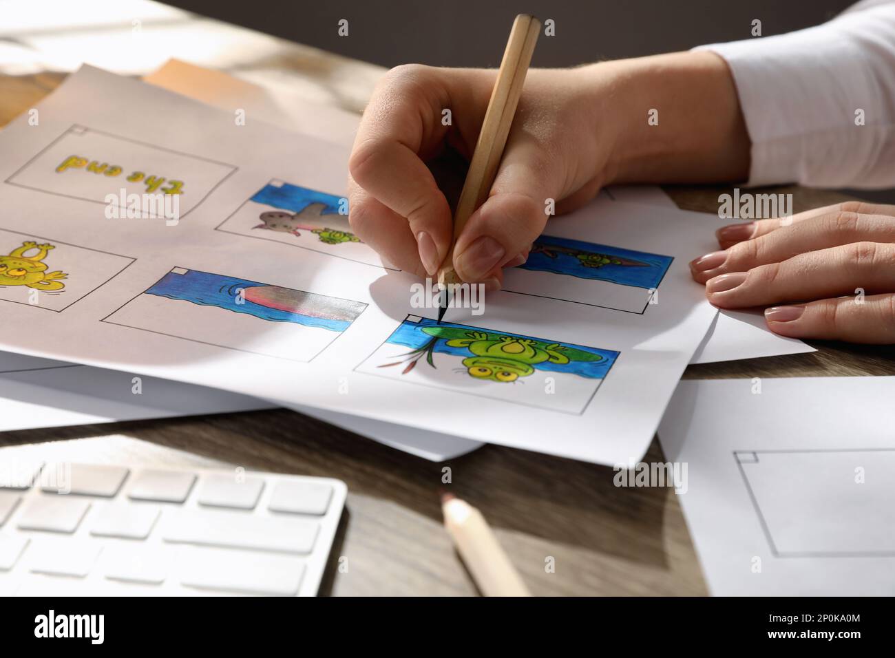 Woman drawing cartoon sketch in storyboard at workplace, closeup. Pre ...