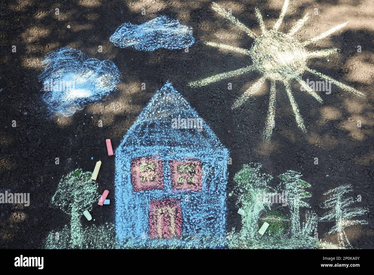 Child's house drawing and pieces of color chalk on asphalt, flat lay ...