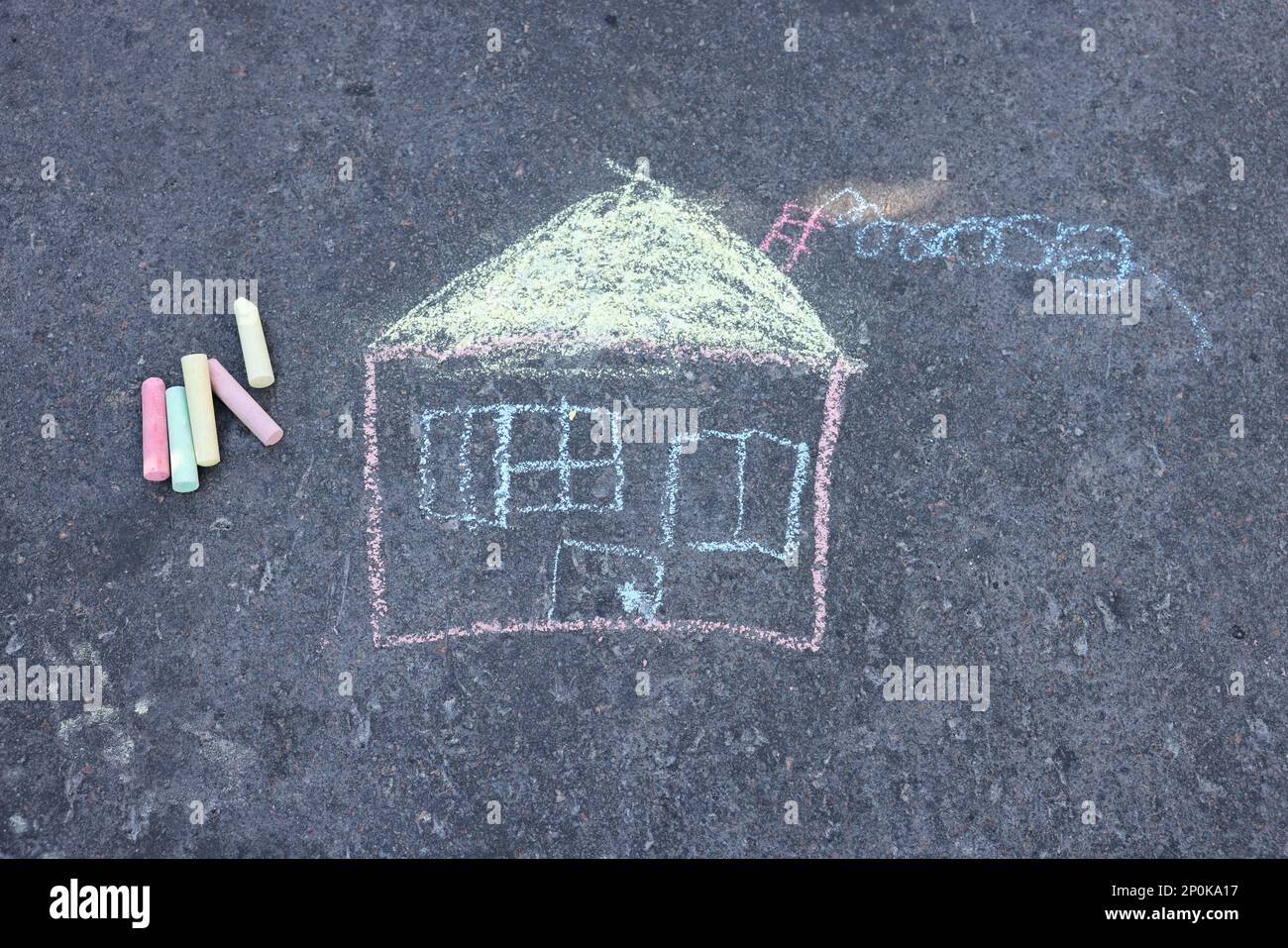 Child's house drawing and pieces of color chalk on asphalt, flat lay ...