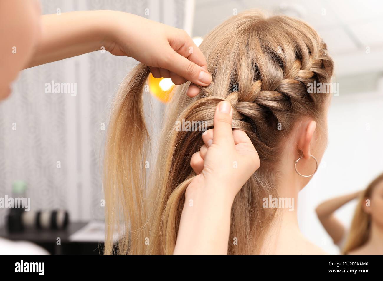 Professional stylist braiding client's hair in salon Stock Photo - Alamy