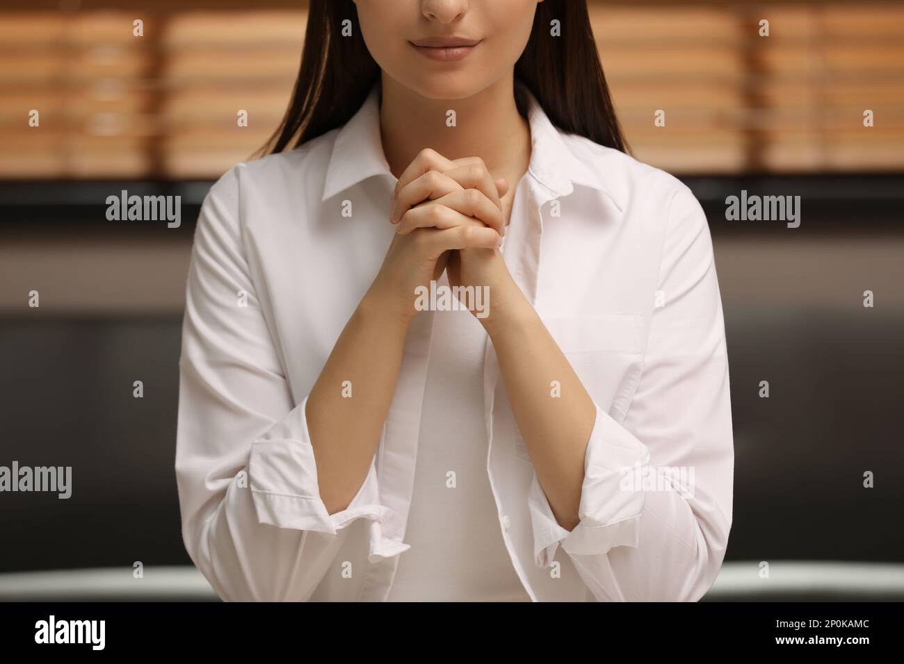 Religious woman with clasped hands praying indoors, closeup Stock Photo ...