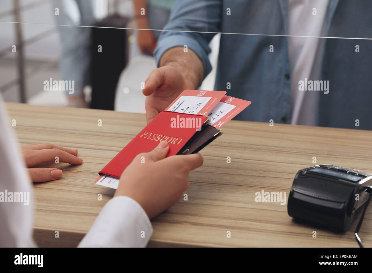 Agent giving passports with tickets to client at check-in desk in ...