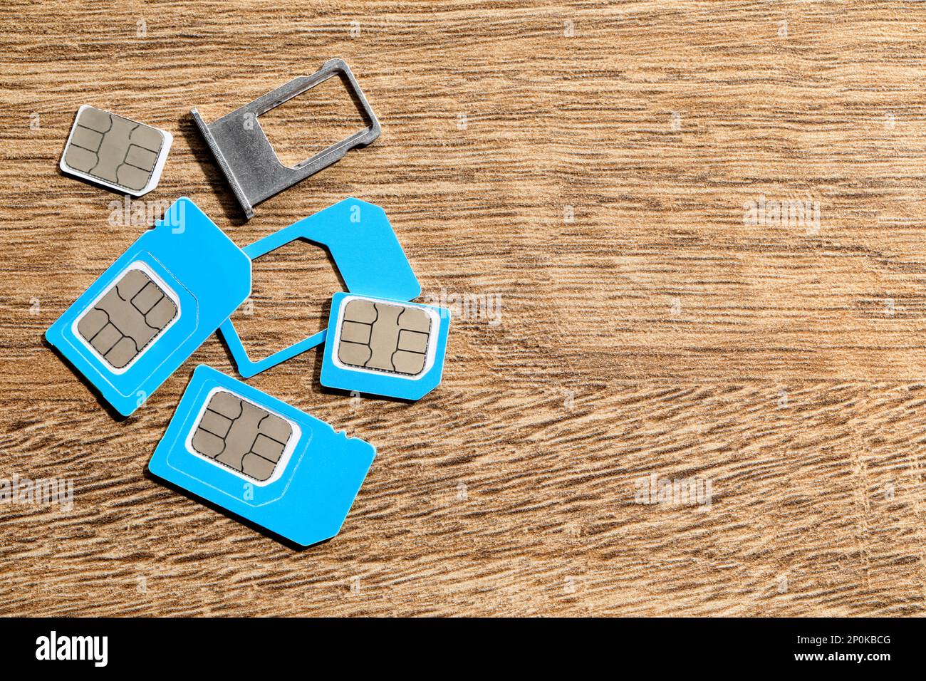 Different SIM cards and tray on wooden background, flat lay. Space for ...